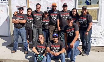 employees standing for a pictures with scheels helping hands t-shirts